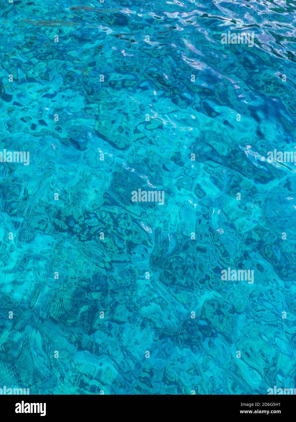 Surface of a crystal clear turquoise water. Sandy sea ground. Sun light ...