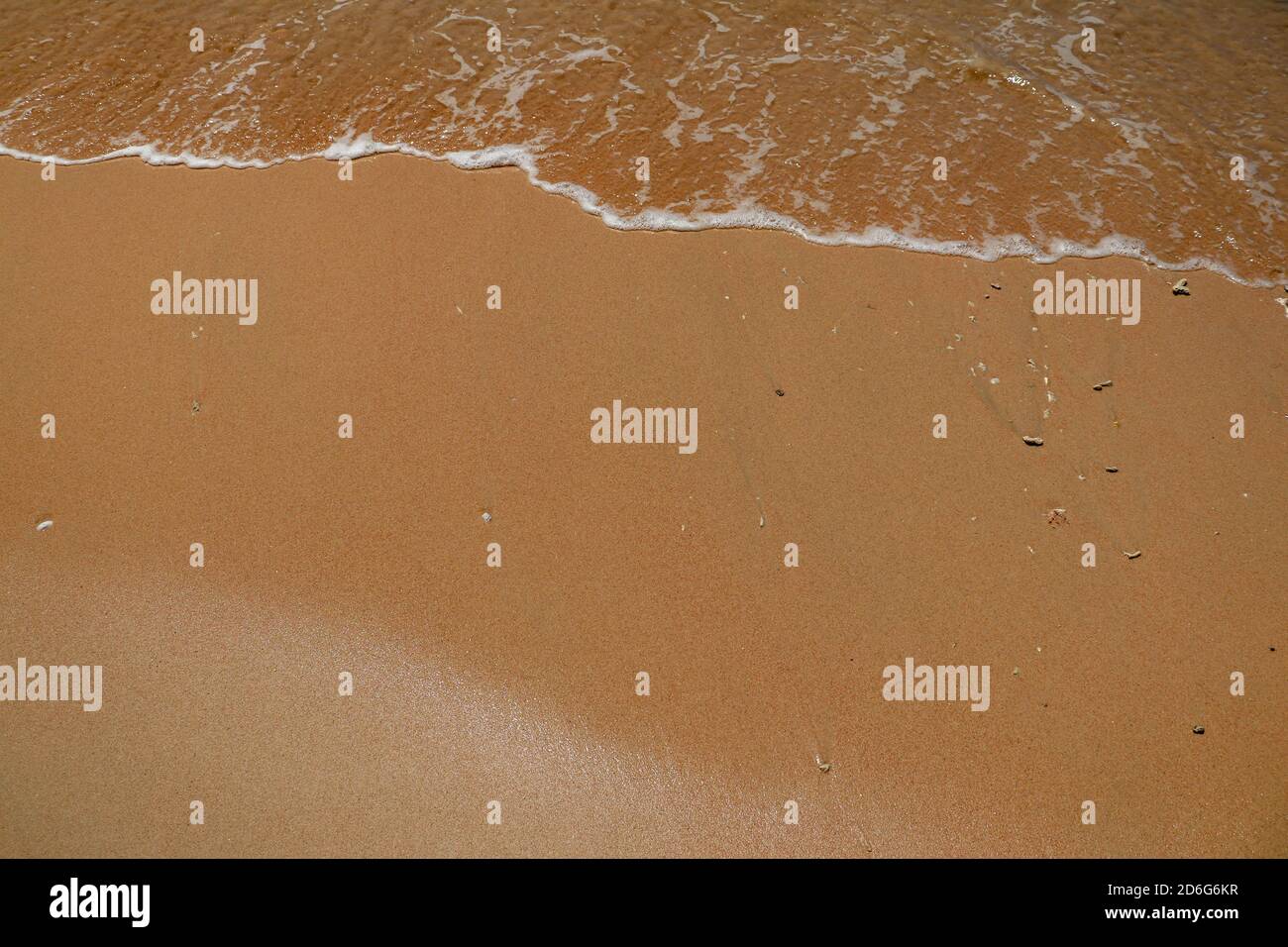 Look from the top corner Bubble waves hit the beach on the wet sand ...