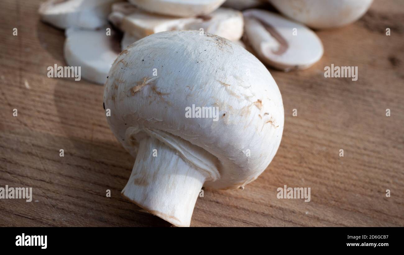 Fluffy bright white mushroom in great close up on wooden cutting board ...