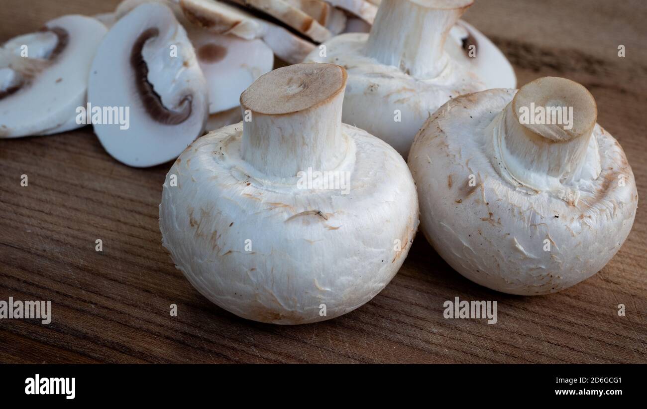 Fluffy bright white mushroom in great close up on wooden cutting board ...