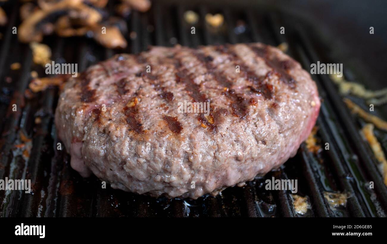 Hamburger patty getting cooked in a cast iron grill pan. Charred burn ...