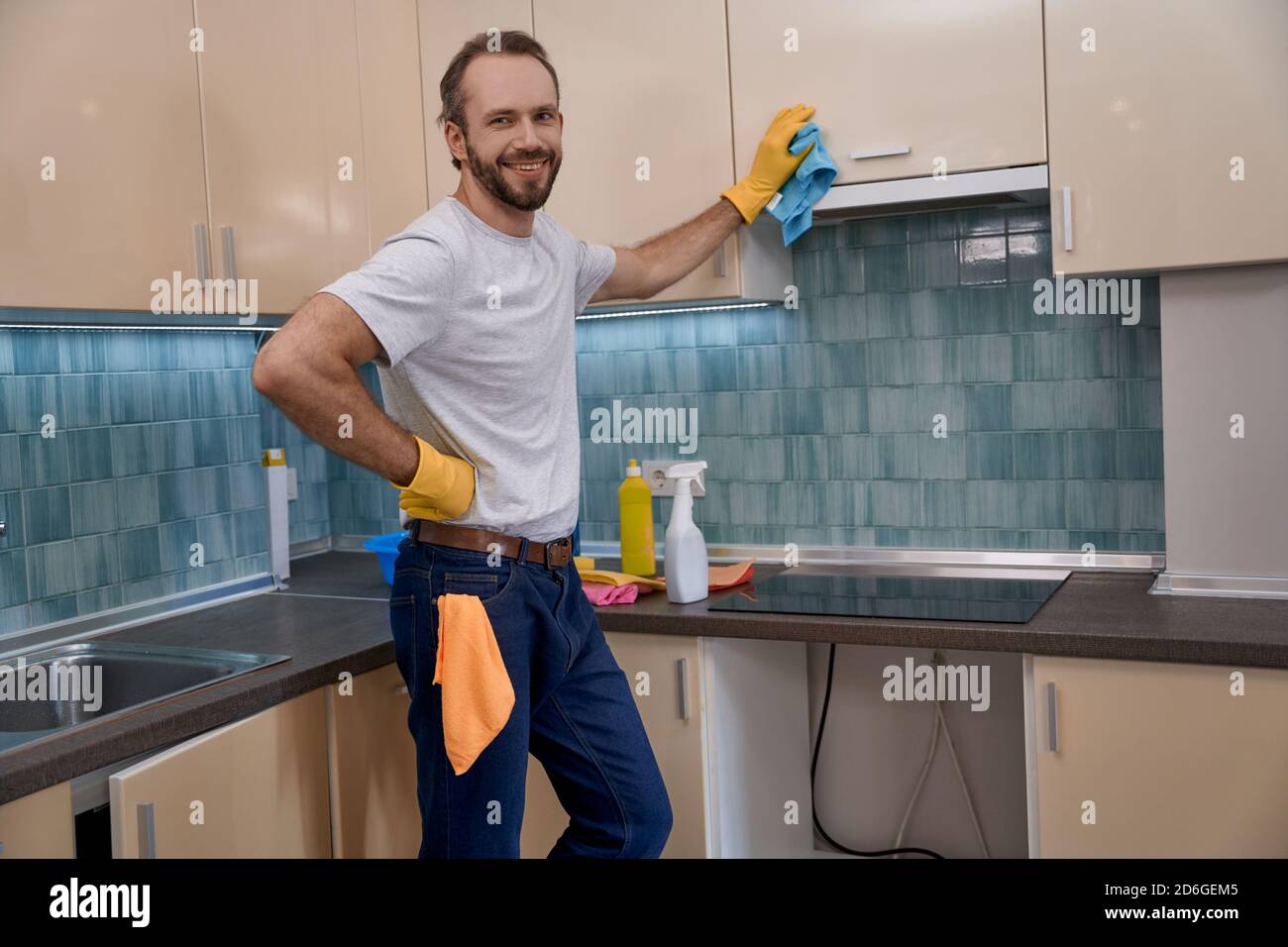 Young caucasian man smiling while cleaning kitchen furniture Stock ...