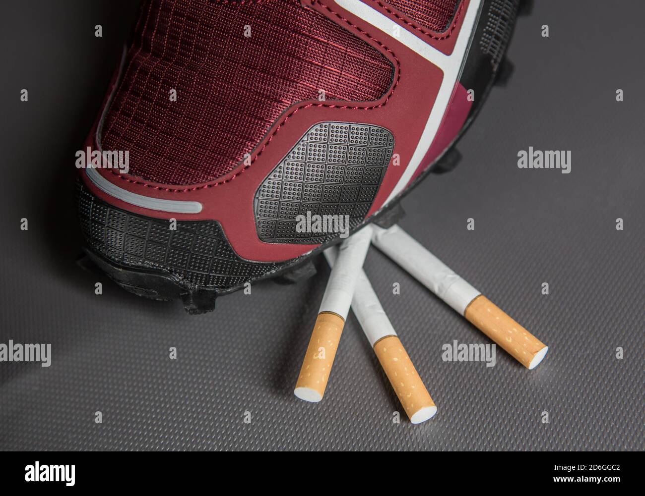 Leg in sneaker treading down cigarettes. Concept of combating smoking ...
