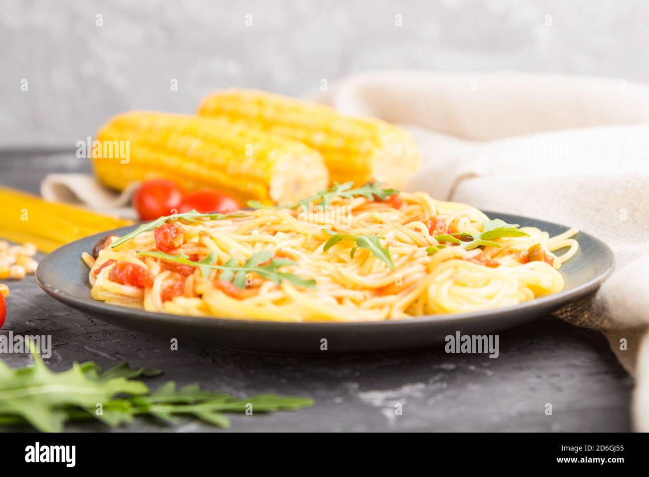 Corn noodles with tomato sauce and arugula on a black concrete ...