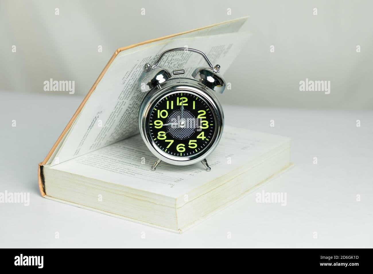 Alarm clock on half open book isolated Stock Photo - Alamy