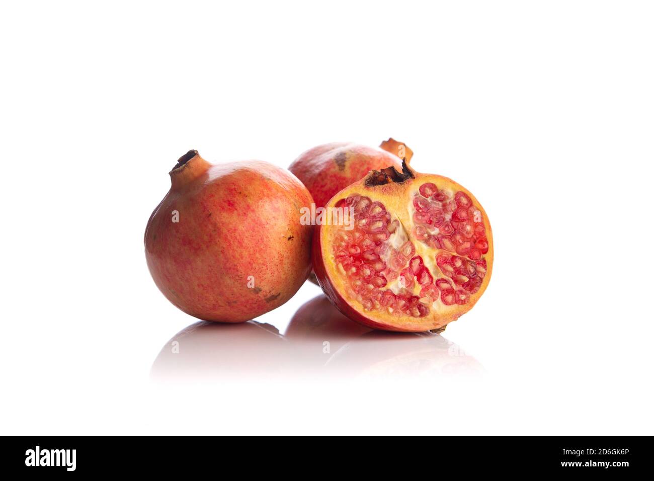 two pomegranate plus one cut in half isolated on white background Stock ...
