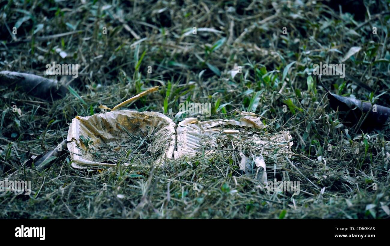 A dirty and worn out piece of plastic food container over a grassy land ...