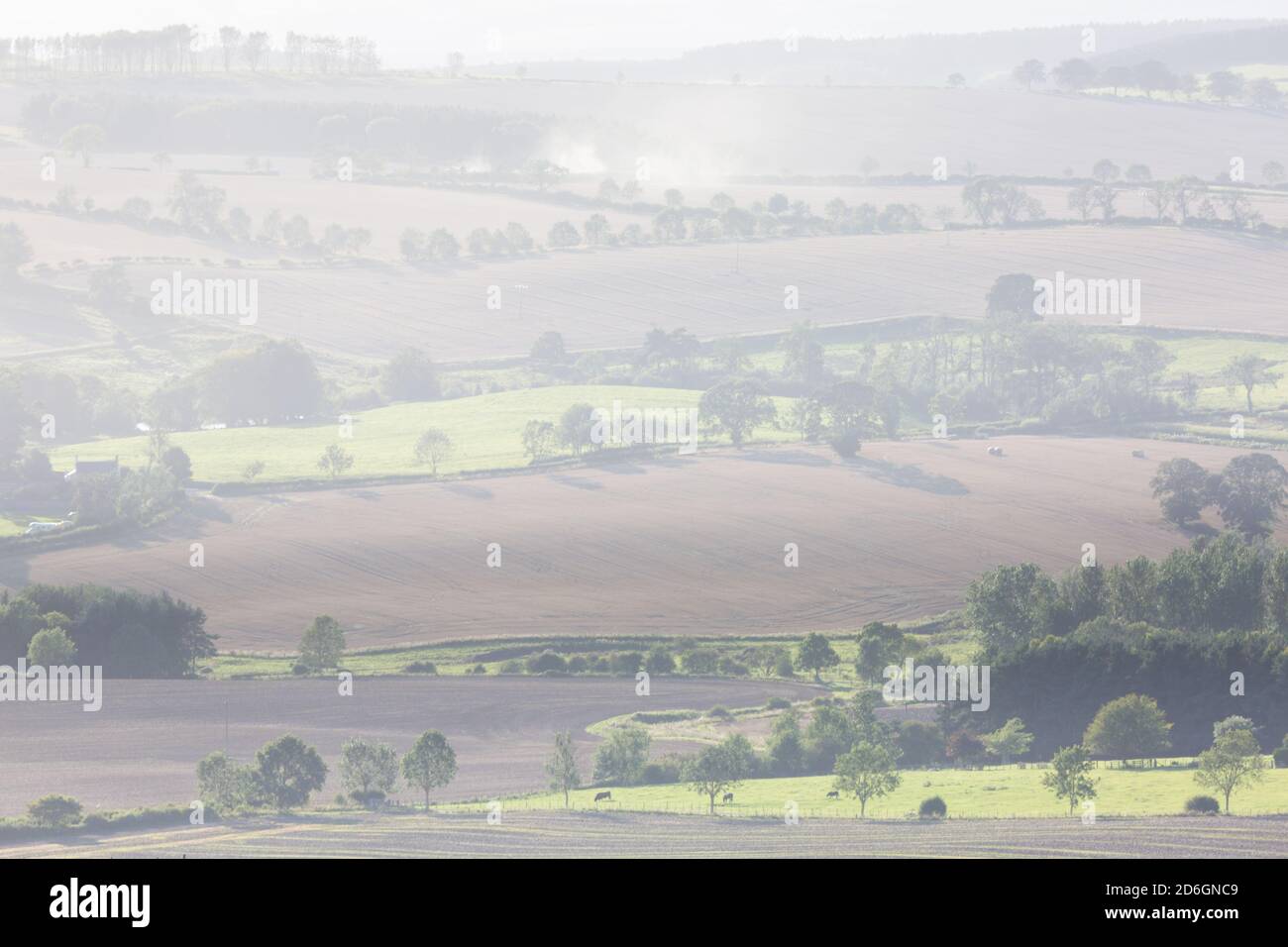 Tractors ploughing fields in the distance in a patchwork of farm fields ...