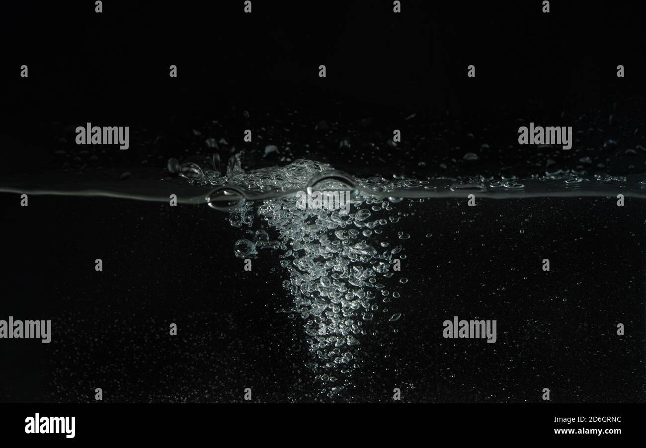 Water splashing as it's poured into aquarium tank, black background ...