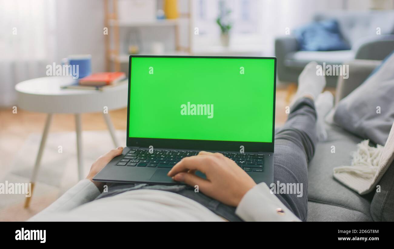 Woman at Home Laying on a Couch using Laptop Computer with Green Mock ...