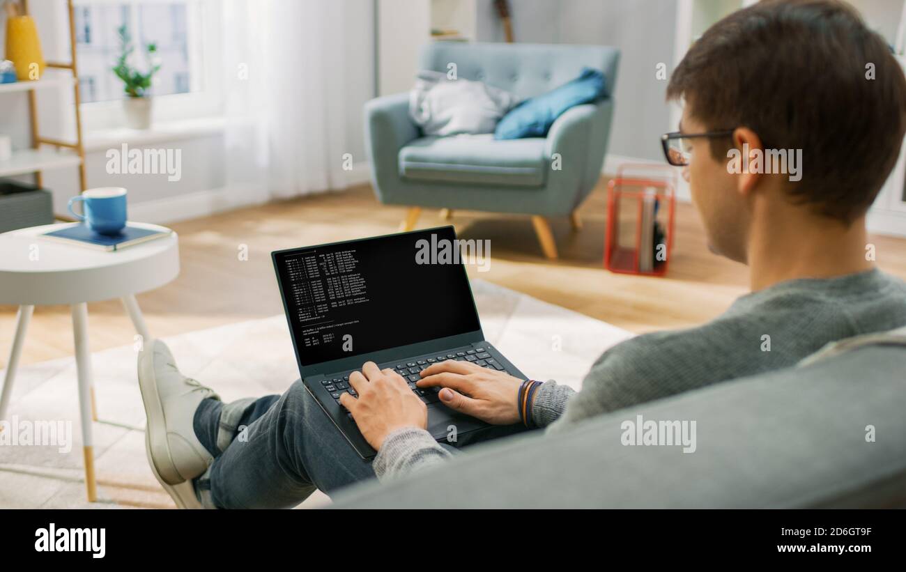 Over the Shoulder Shot: Young Male Programmer Wearing Glasses Works on ...