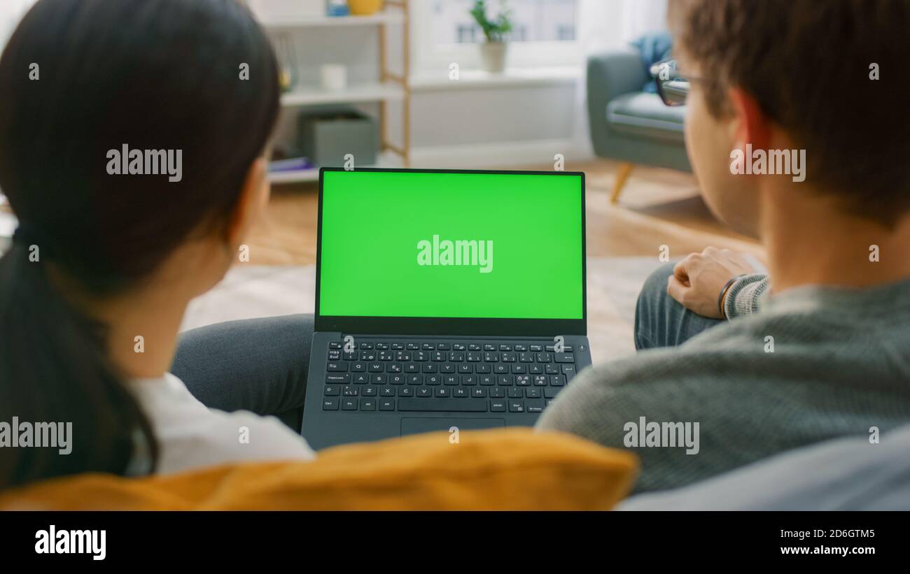 Young Man and Woman at Home Using Green Mock-up Screen Laptop Computer ...