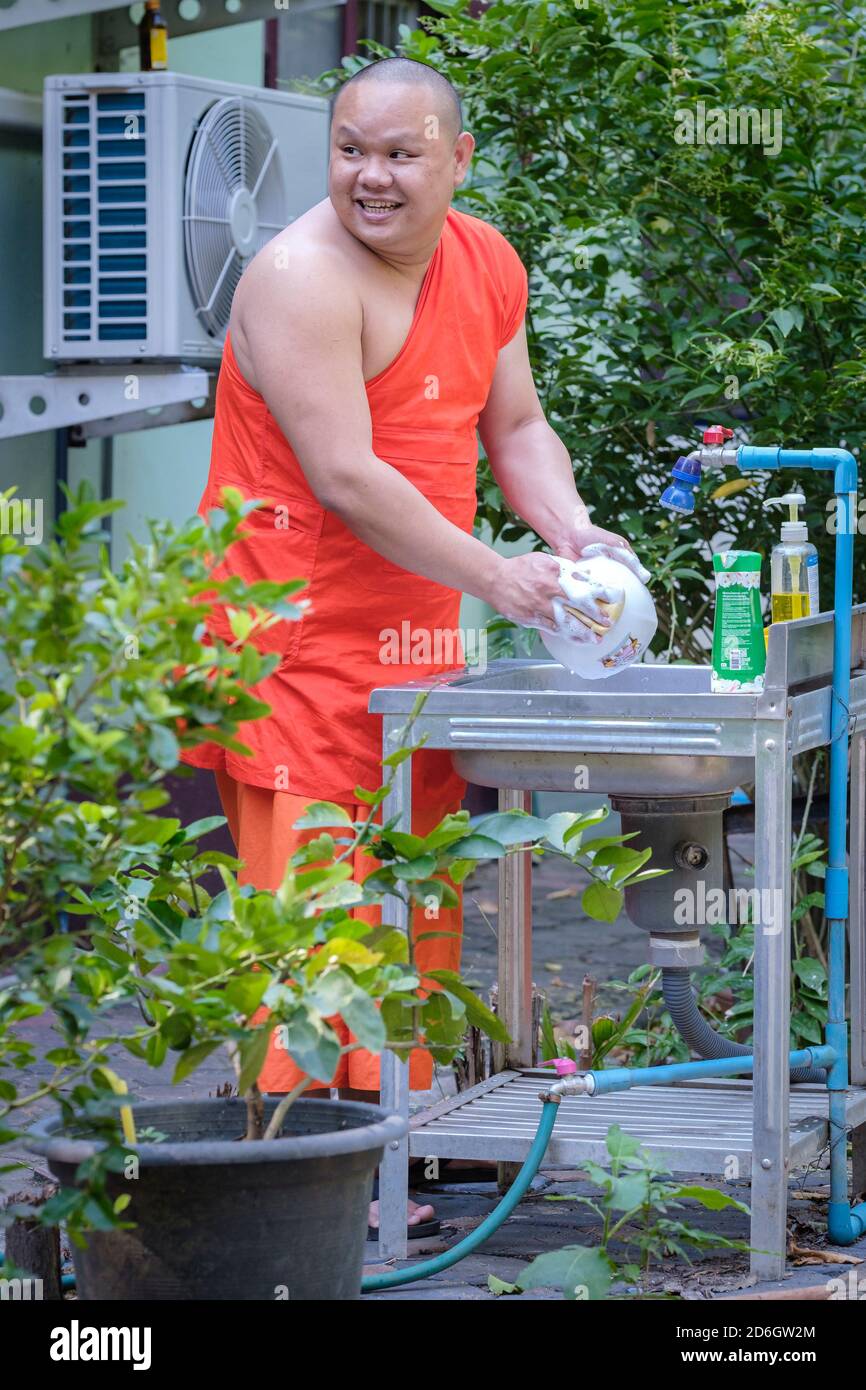 Monk washing dishes outside his temple sleeping quarters, Wat Suandok ...