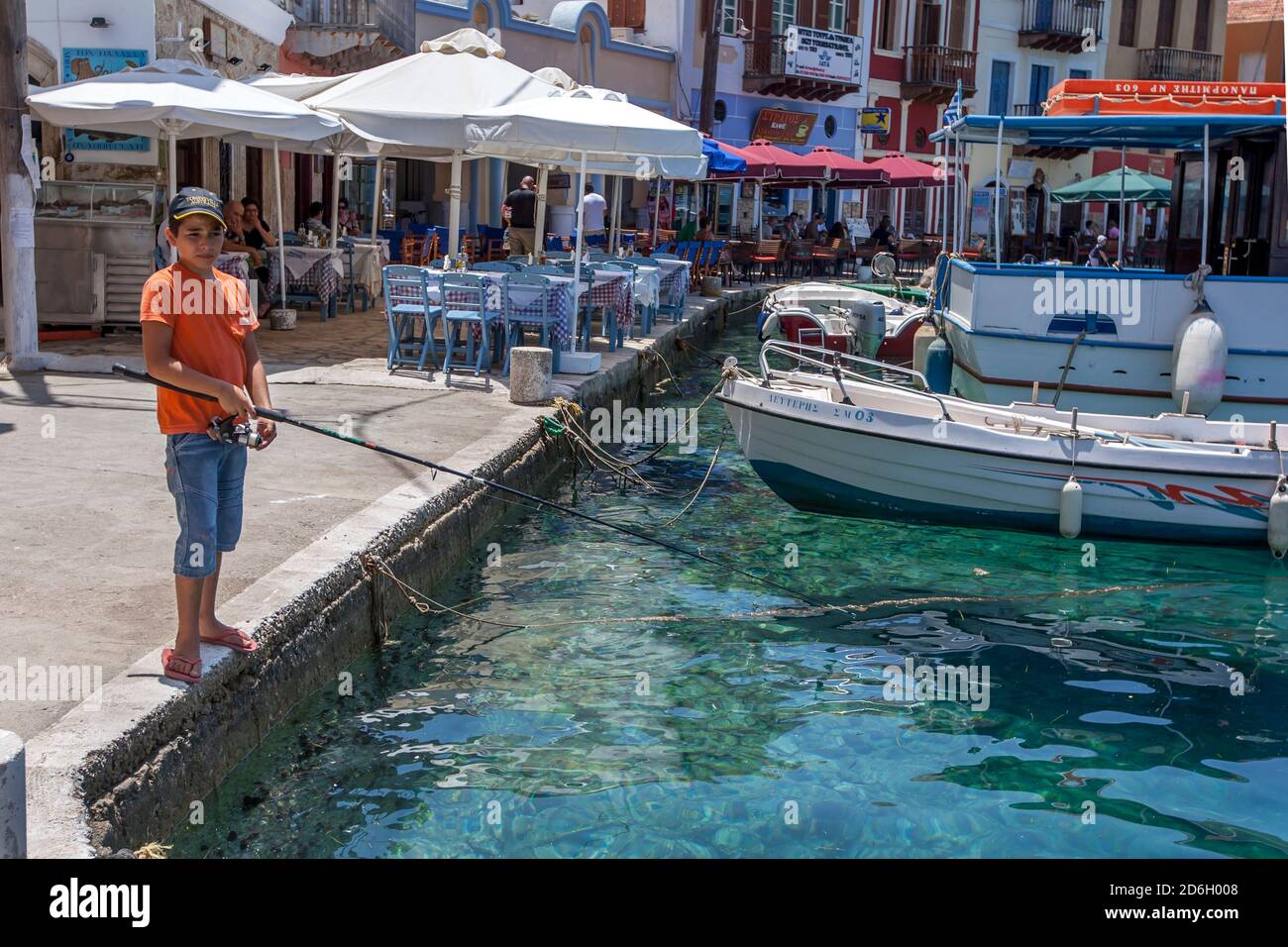 A boy fishing in the harbour of the Greek island of Kastellorizo ...