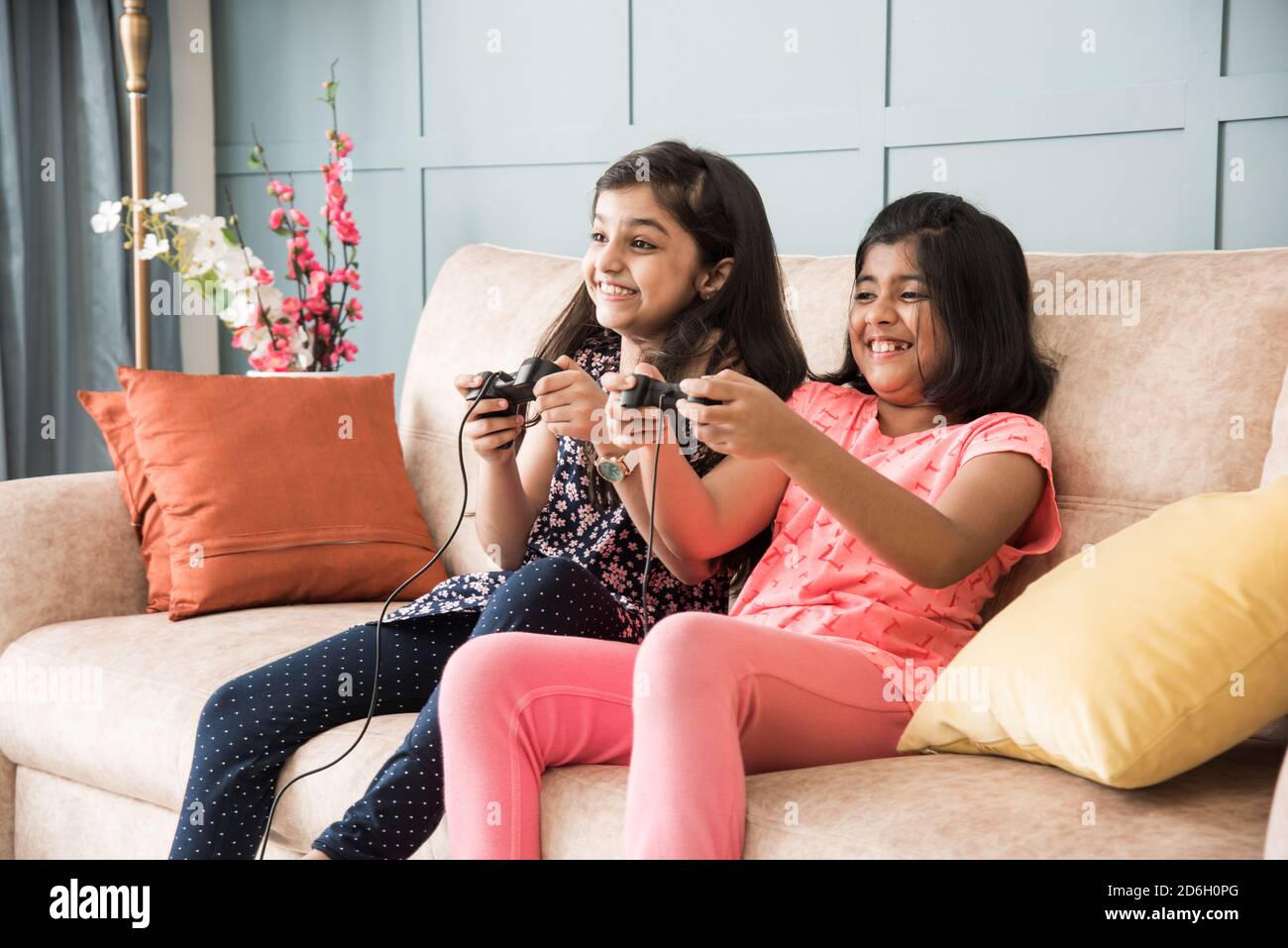 Cheerful Indian Asian kids playing video game using joystick or ...