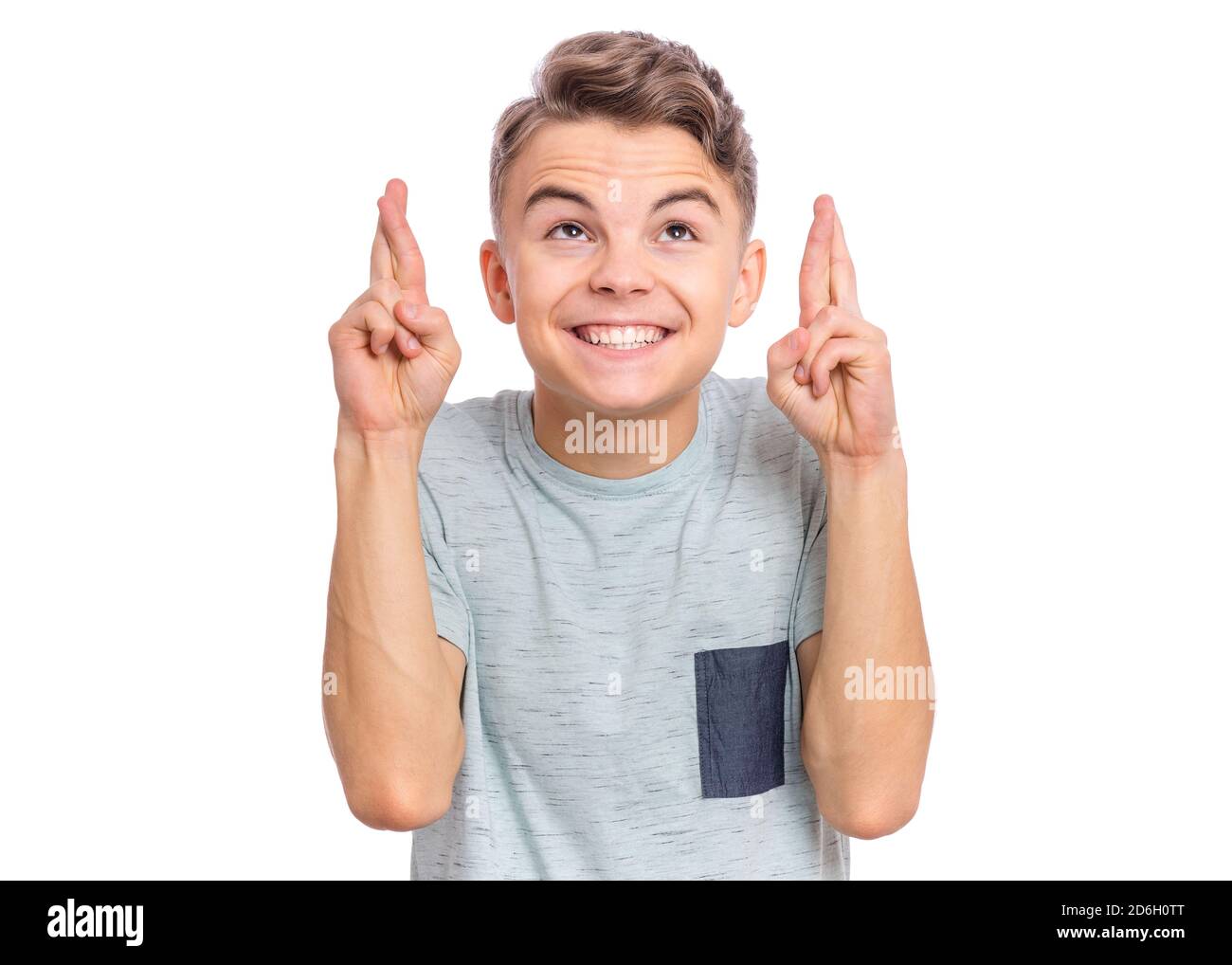 Handsome teen boy looking very happy holding fingers crossed for good ...