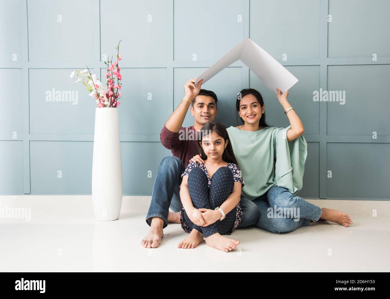 Indian family Father, mother, son and daughter holding House roof made ...