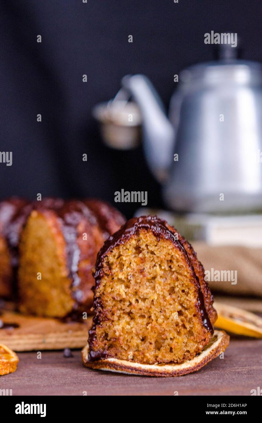 pumpkin muffin slice with chocolate icing in the foreground on black ...