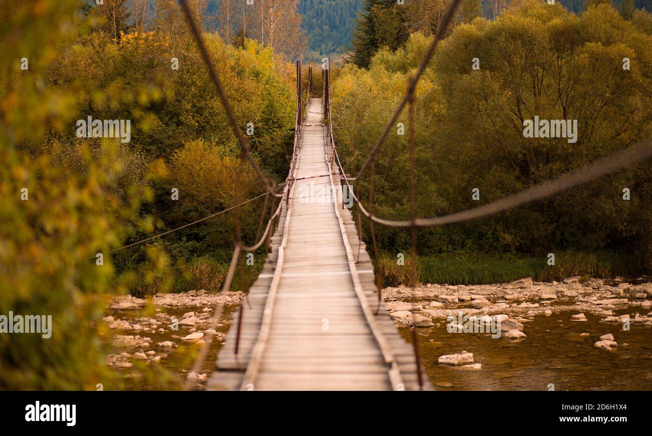 Landscape view of long wooden suspension bridge over mountains river ...