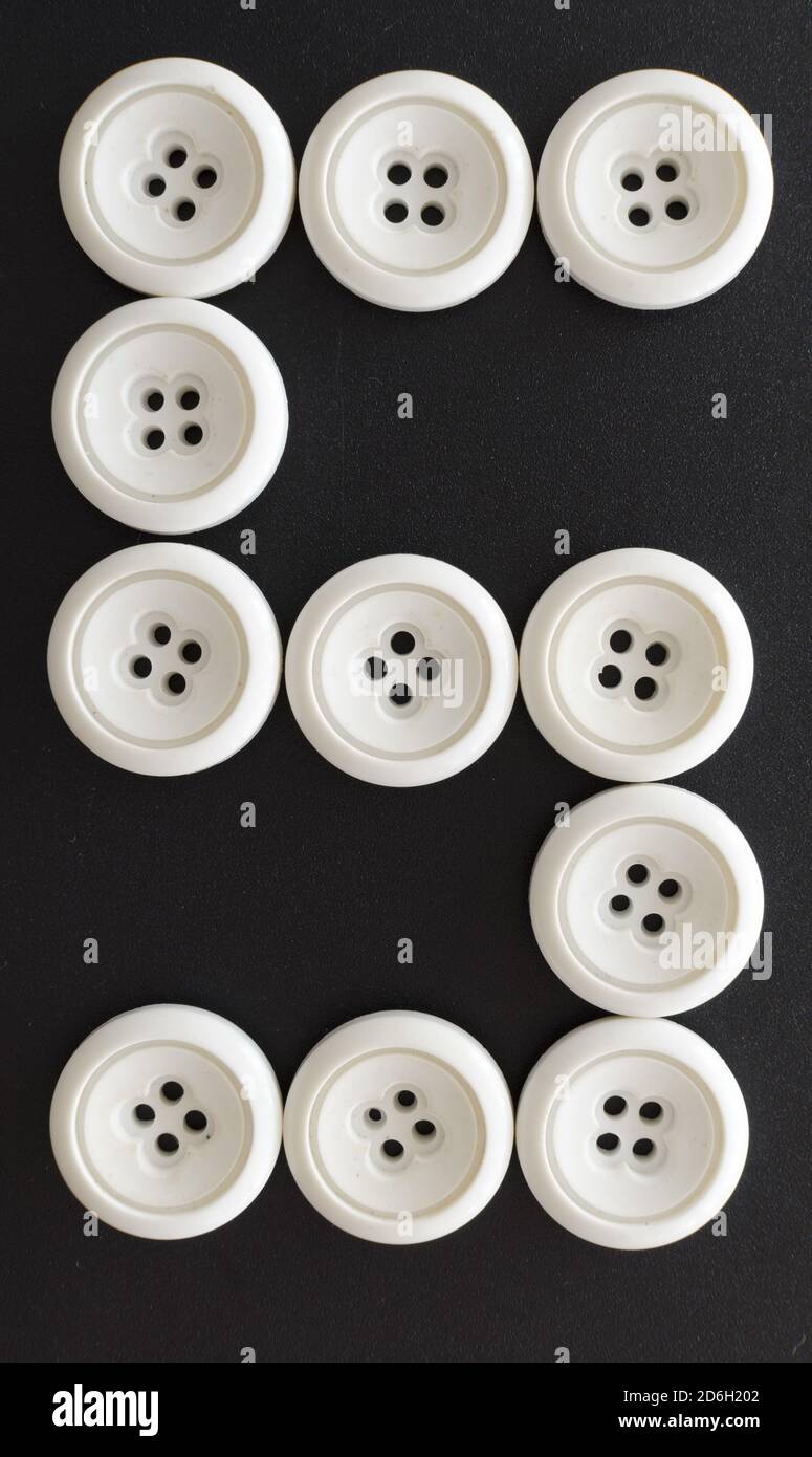 Vertical shot of white buttons assorted like the number five on a black ...