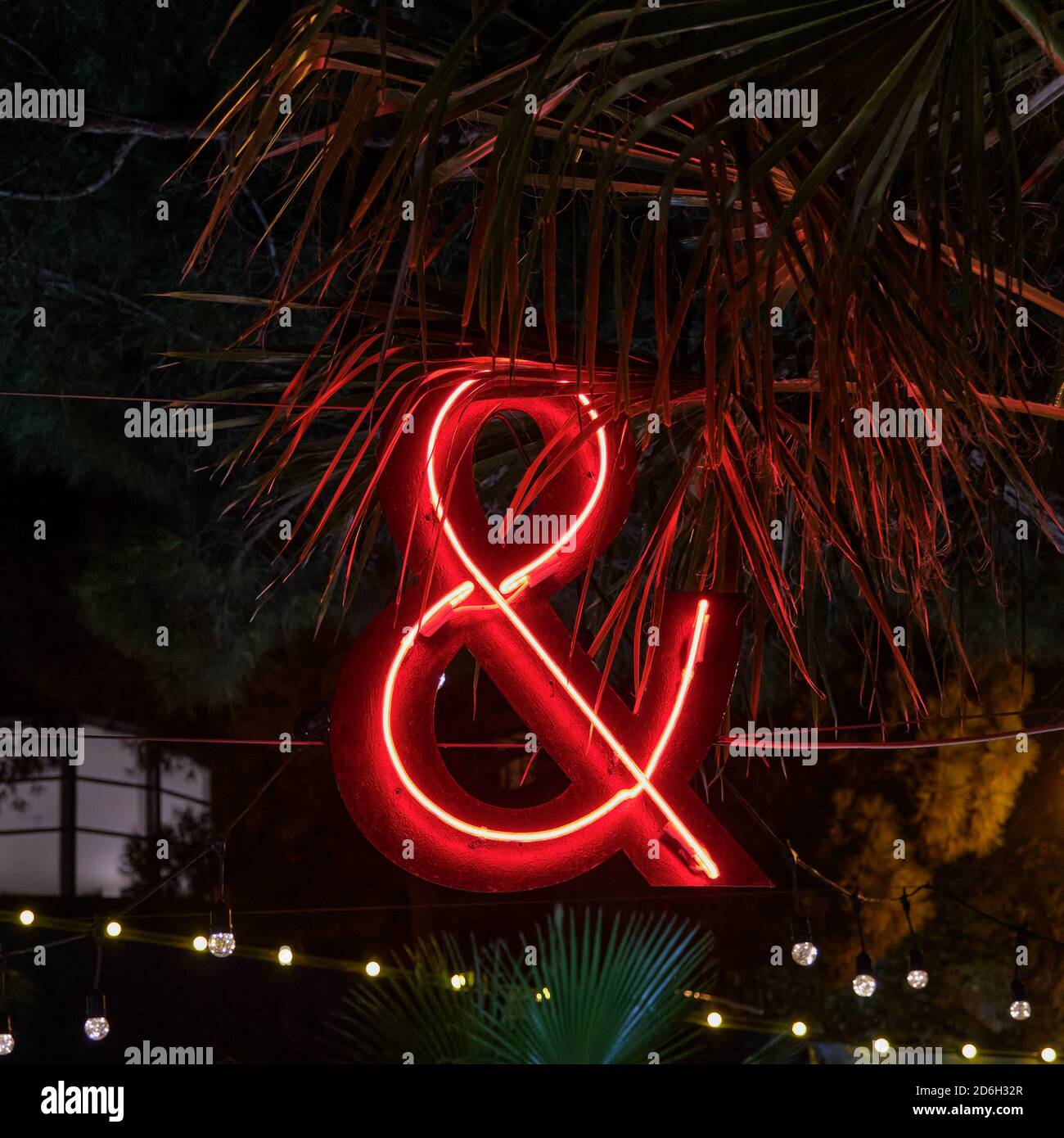 Evening lighting in the form of a luminous neon red ampersand sign on ...