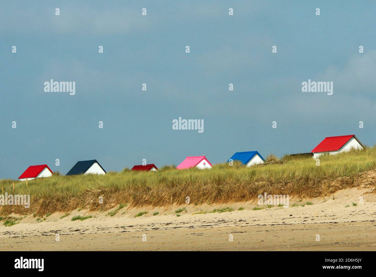 The tiny white beach cottages with colorful roofs at a beach by ...