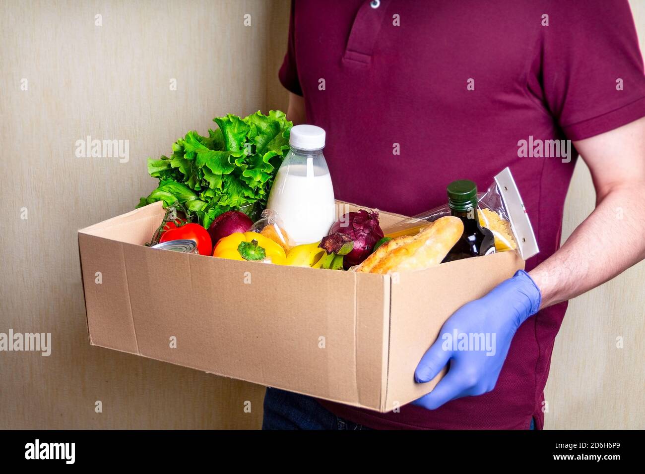 Volunteer in gloves holding food in a donation cardboard box with ...