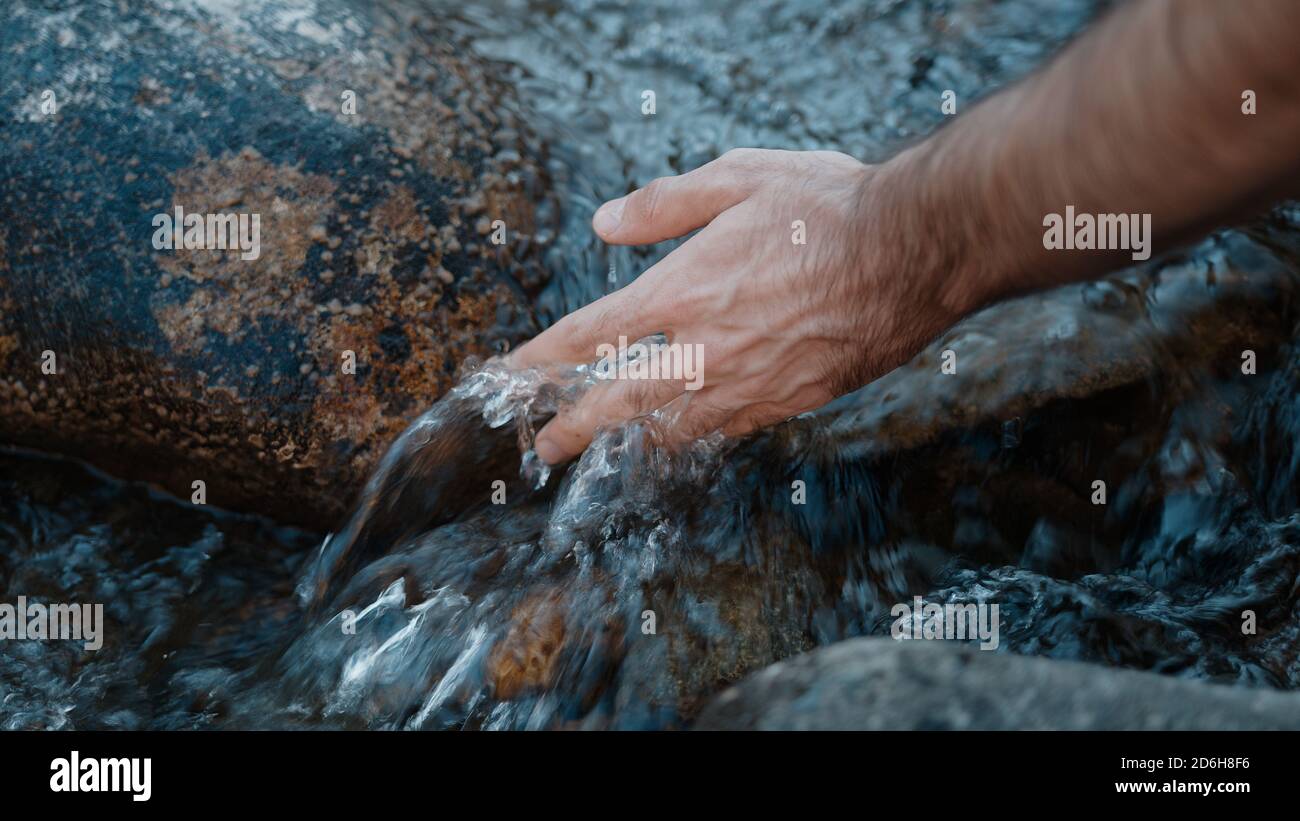 Person hand put in the flowing river or stream and is captivated by the ...