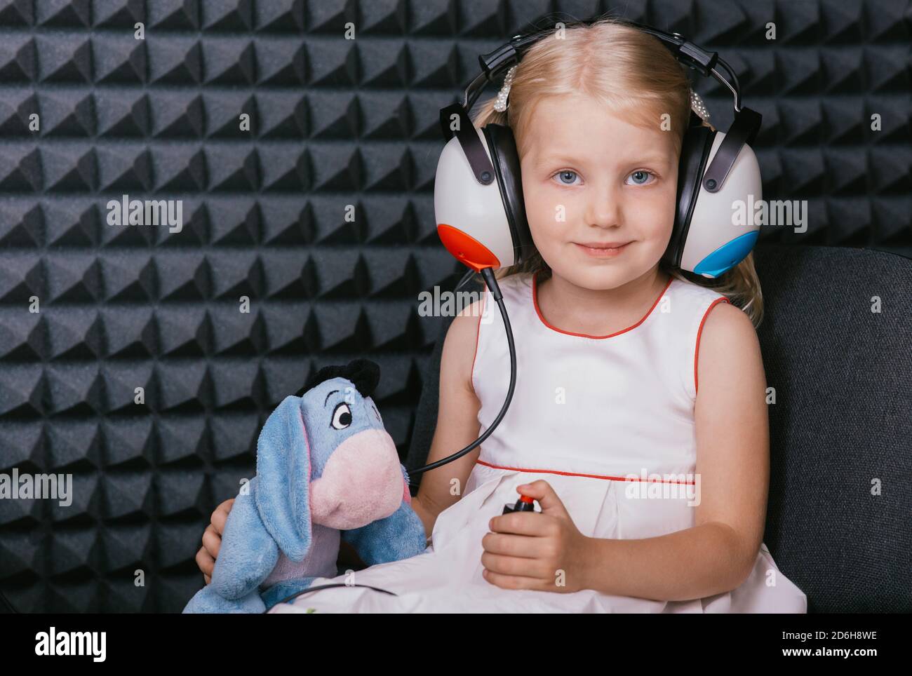 Positive little caucasian girl wearing headphones having a hearing exam ...