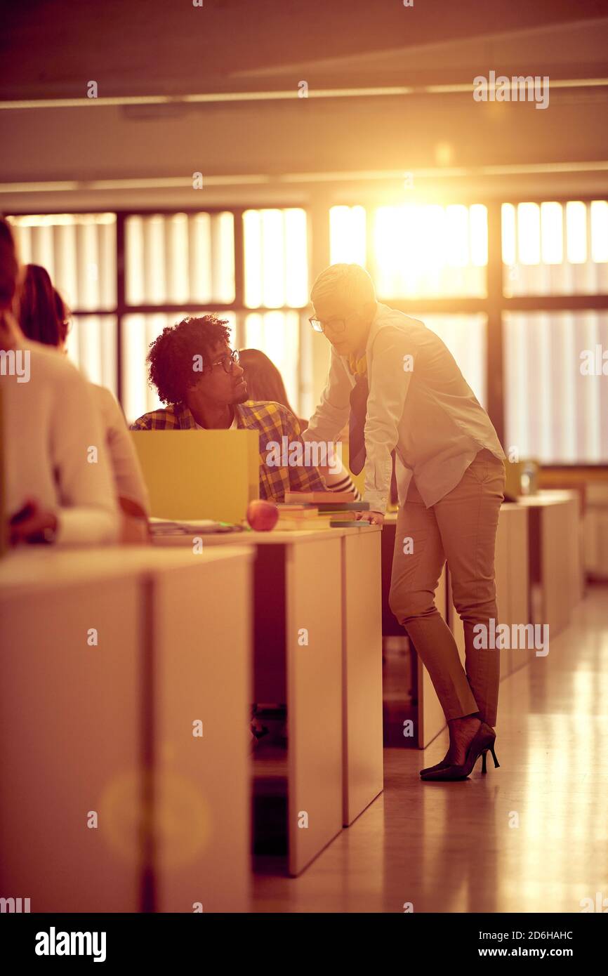 Male student asking professor questions about the lesson at a lecture ...