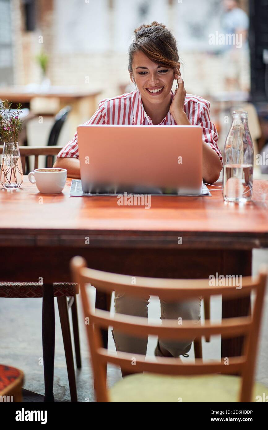 Young beautiful girl at a cafe relaxed with a coffee working on laptop ...