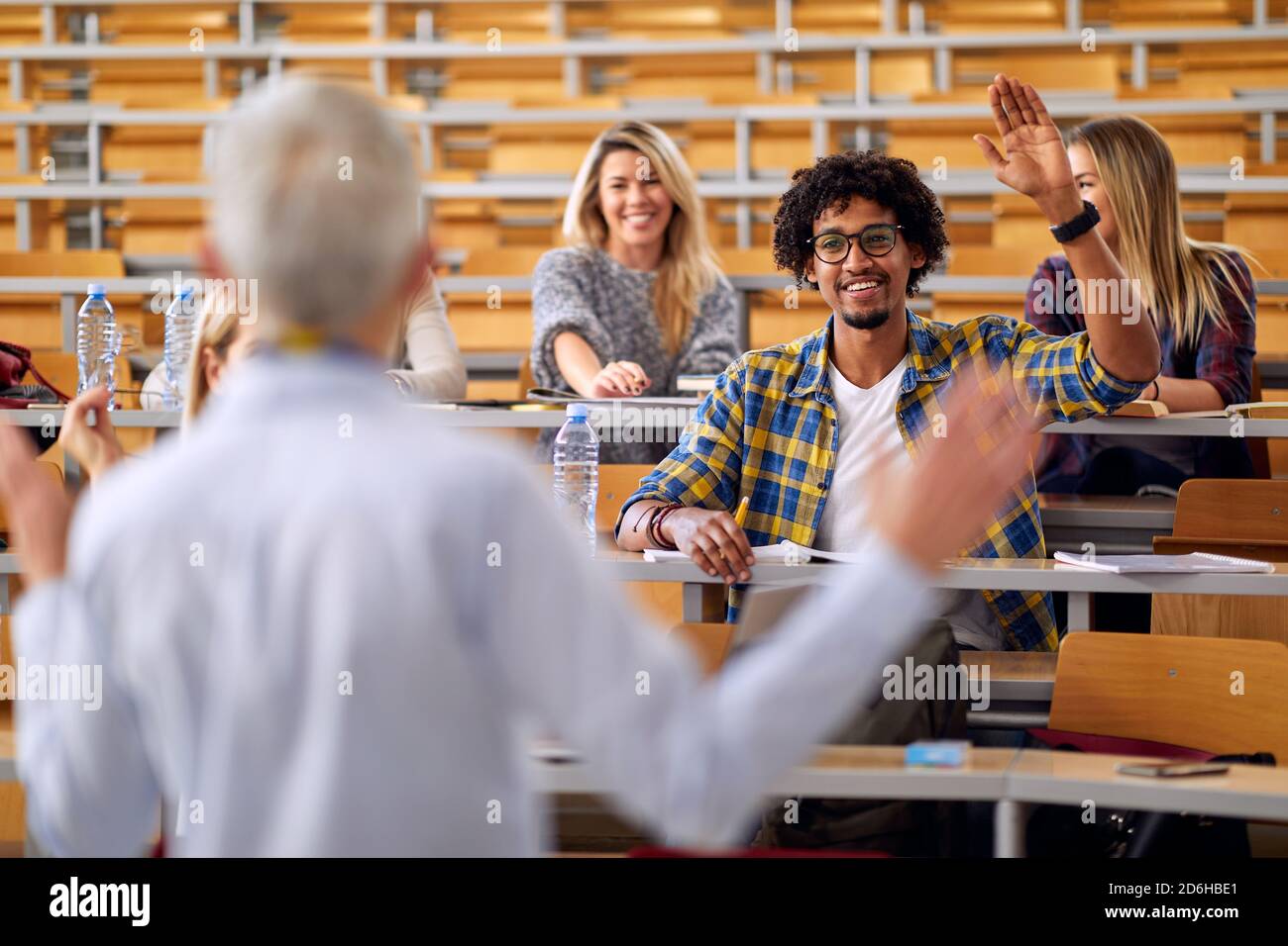 Male student raising the hand to answer the professor question at the ...