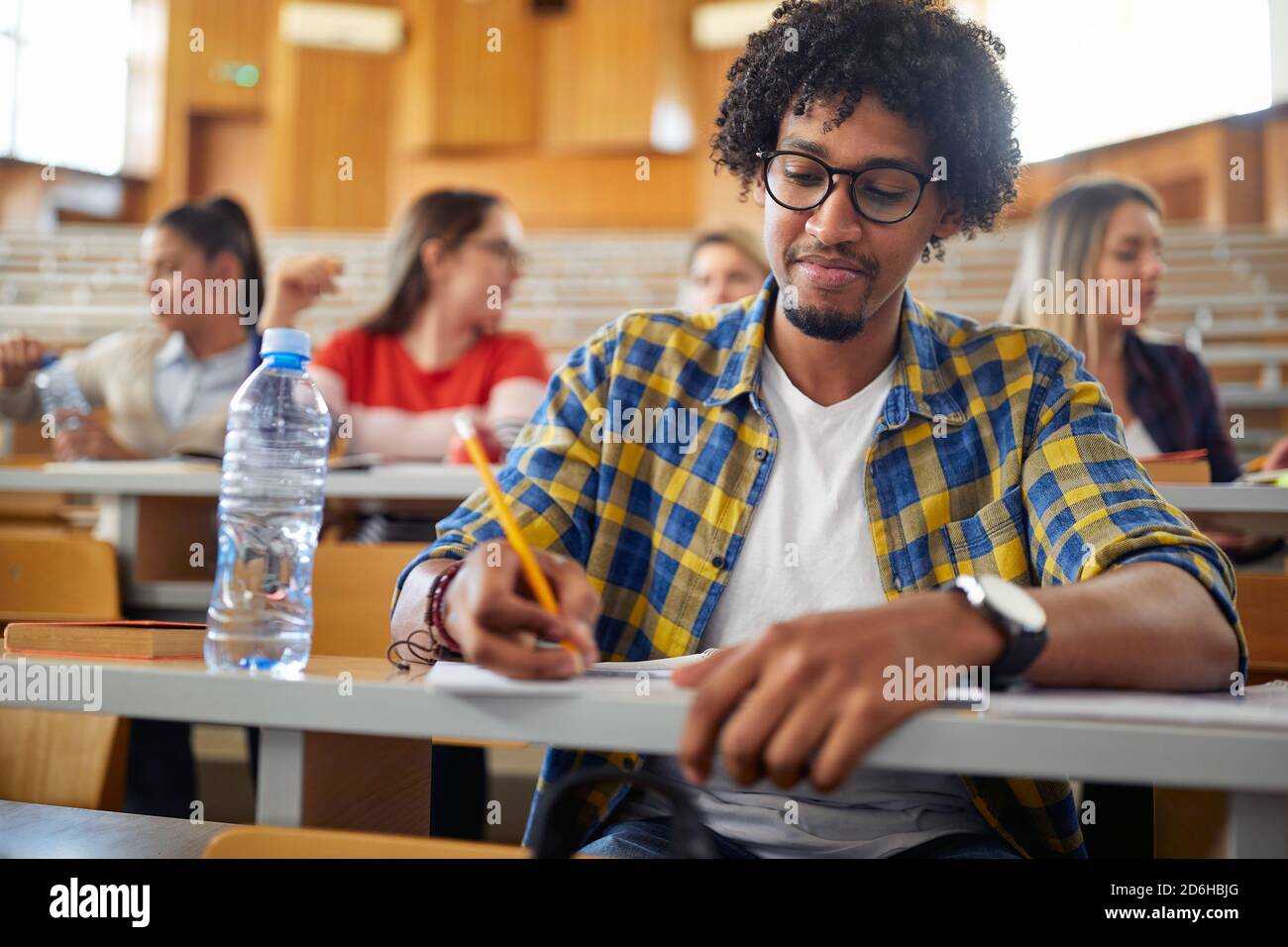 Male student writing down the notes at the lecture in the university ...