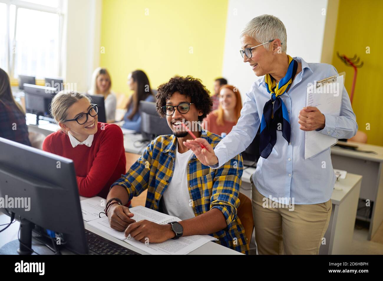 A female professor giving help to students at the informatics lecture ...