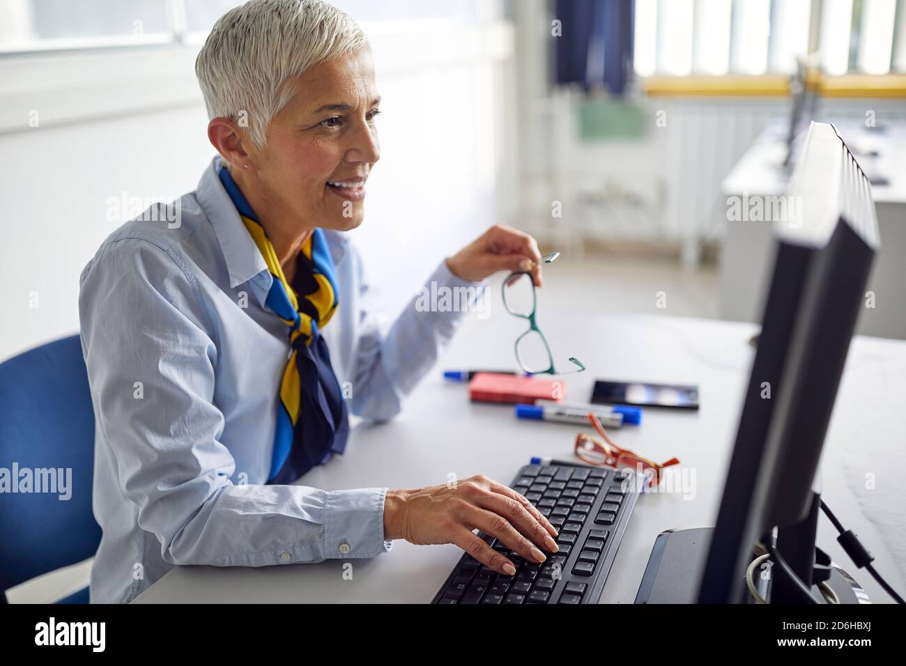 A female professor typing on a computer at a lecture in the university ...