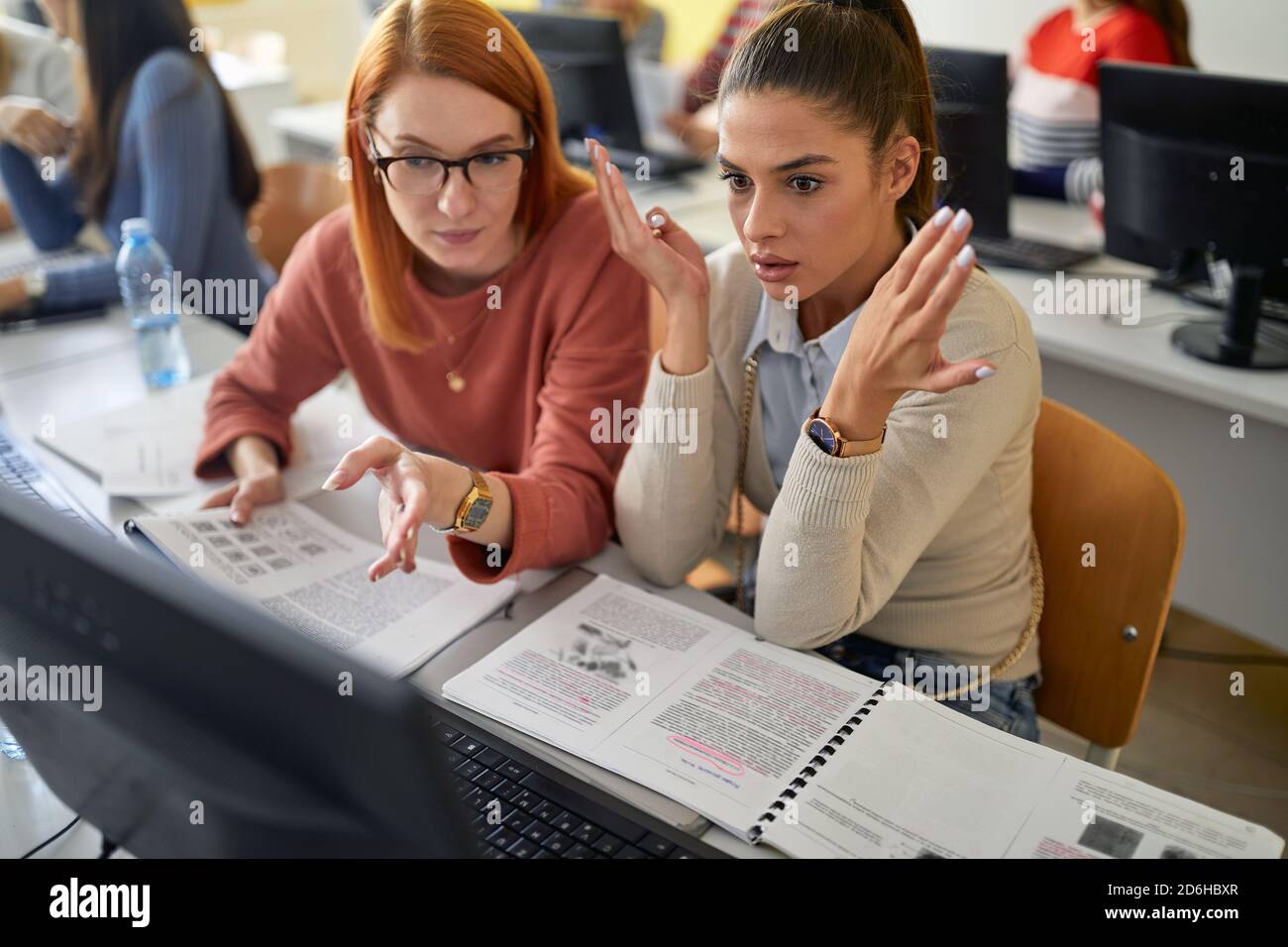 A female student giving help to a colleague at the informatics lecture ...