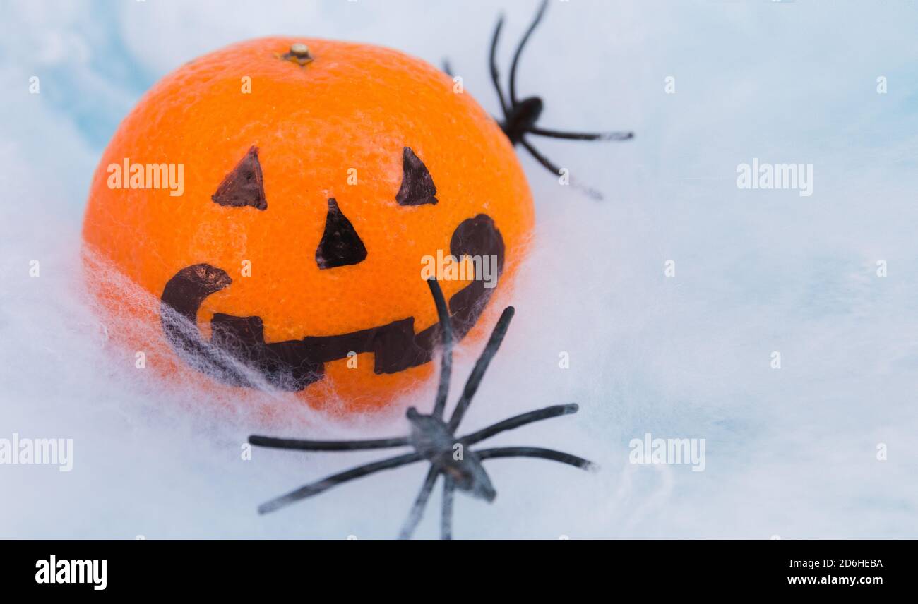 Bright orange Halloween scary tangerine emotion face on white spider ...