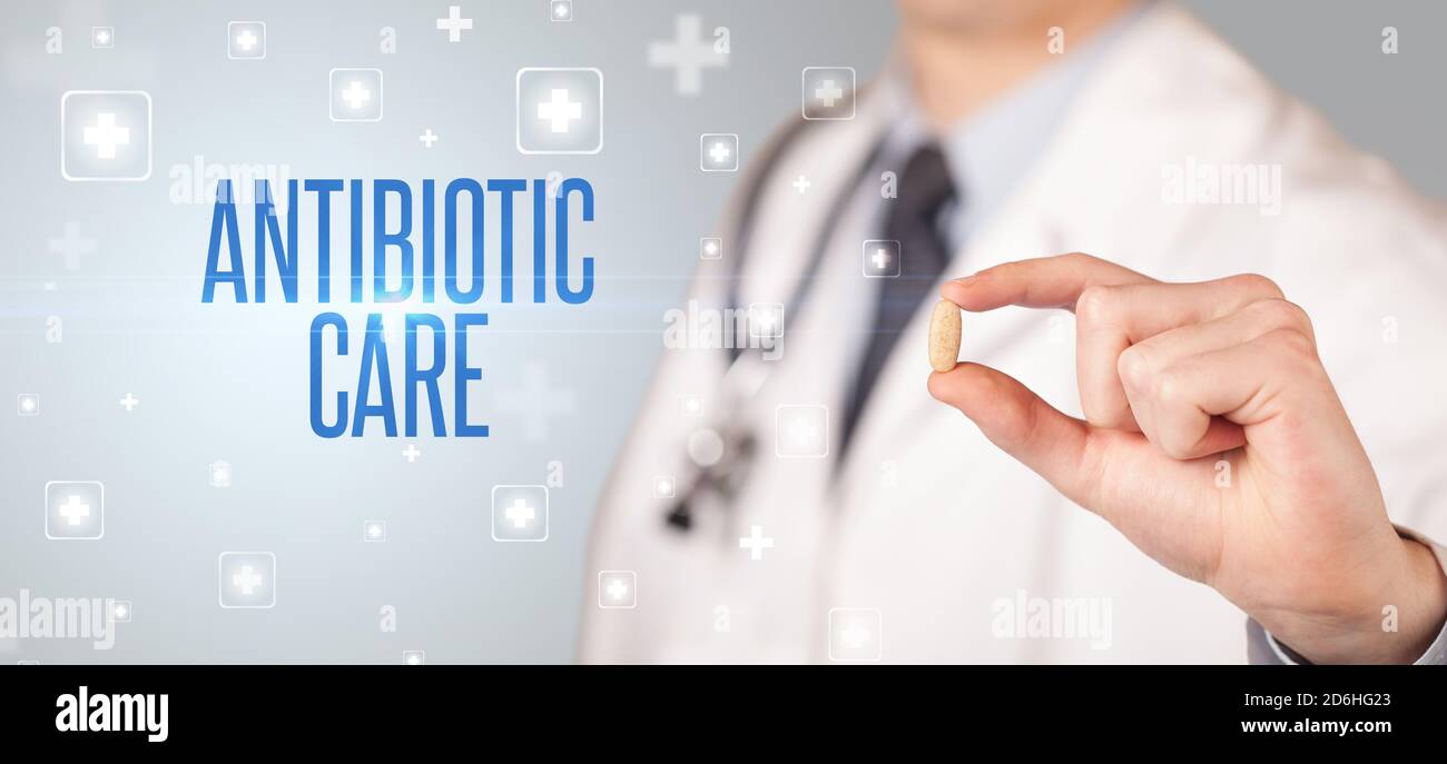 Close-up of a doctor giving a pill with ANTIBIOTIC CARE inscription ...