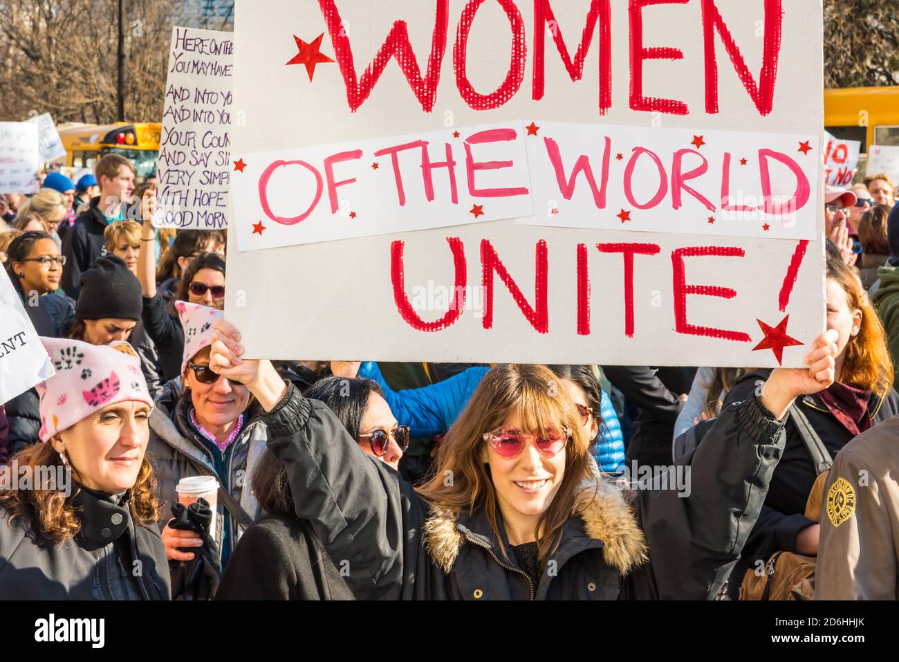 A Woman In A Crowd Of Other People Holding Up A Sign Women Of The