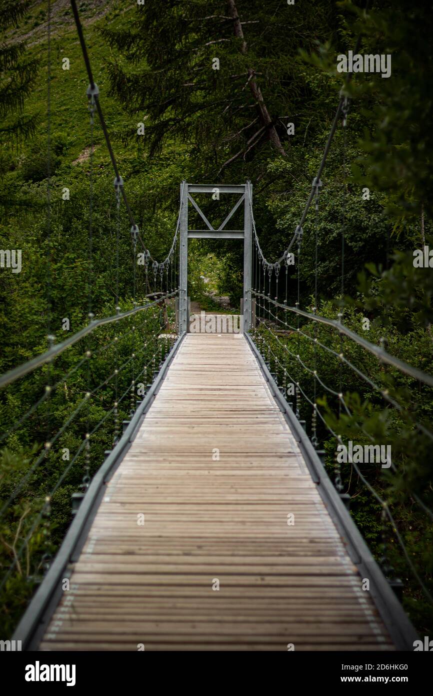Wooden long footbridge above the deep gorge with a river beach at the ...