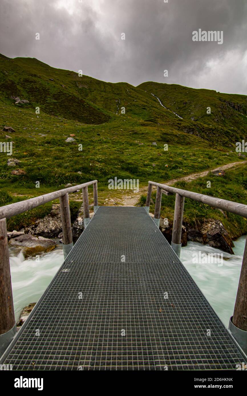Wooden long footbridge above the deep gorge with a river beach at the ...