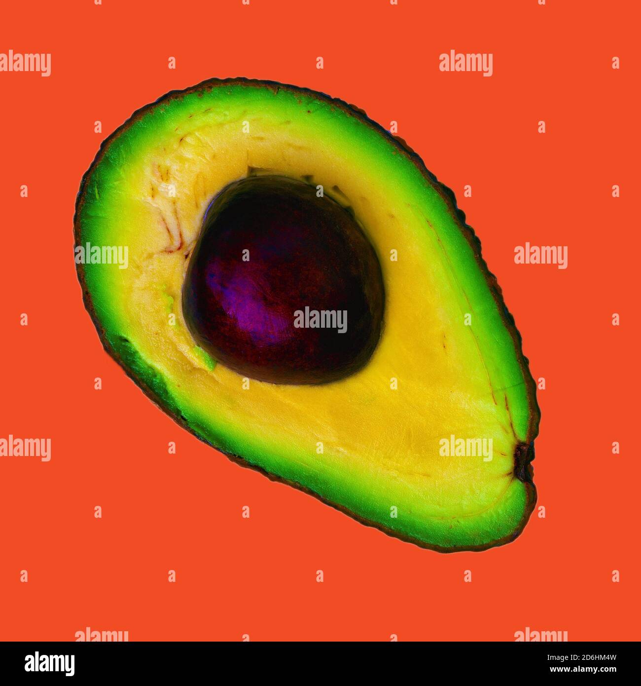 Bright colored avocado cut in half isolated on lush lava color ...