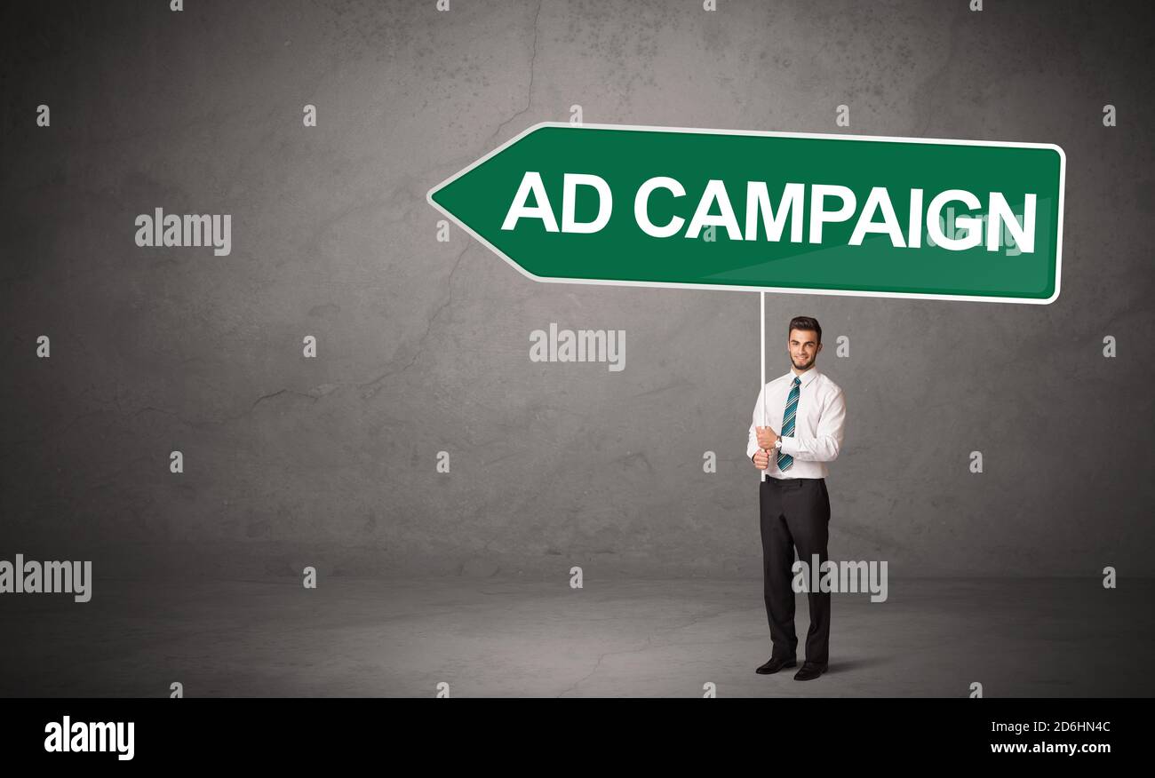 Young business person in casual holding road sign with AD CAMPAIGN ...