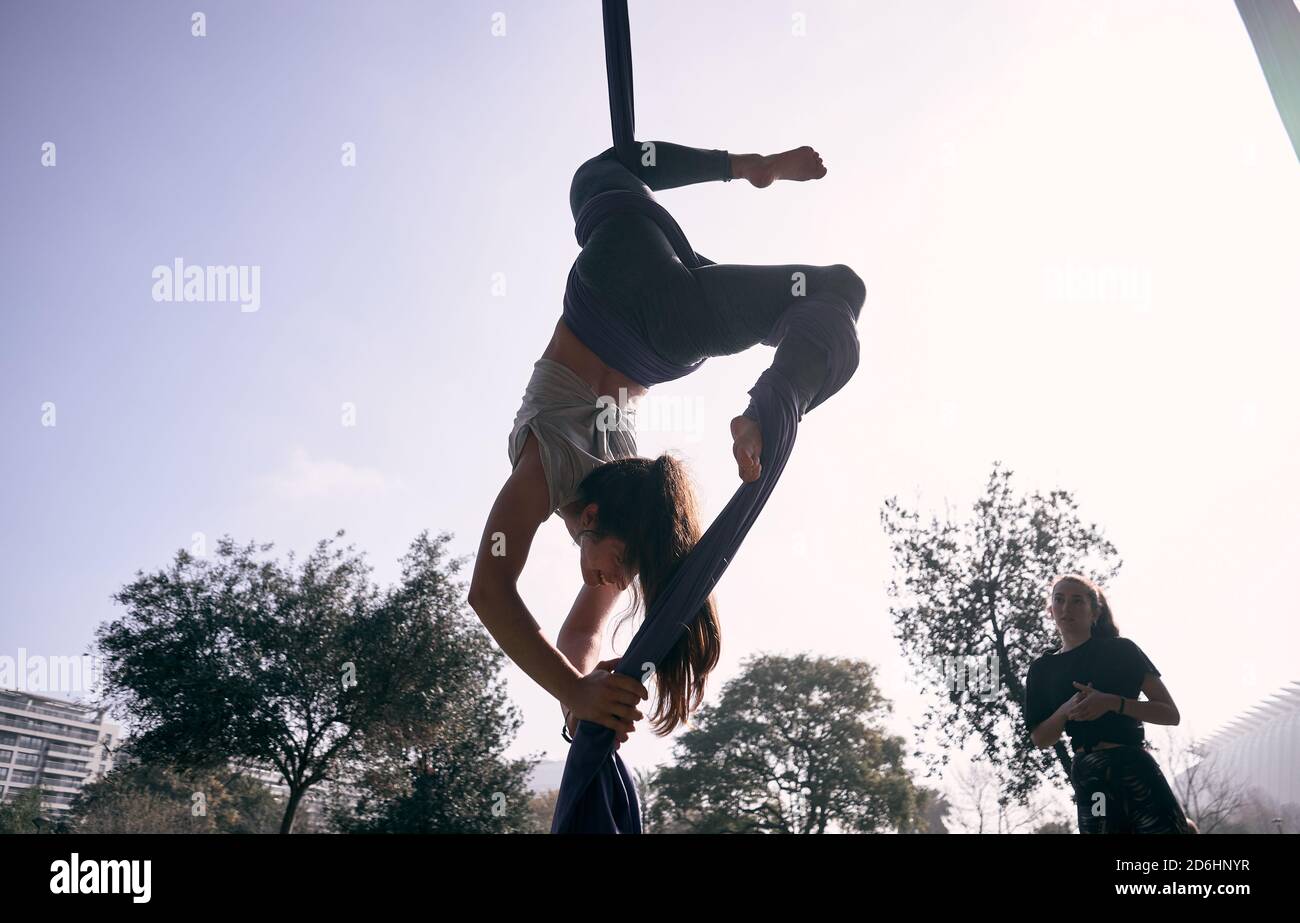 Young Caucasian woman practicing aerial silks performance while hanging ...