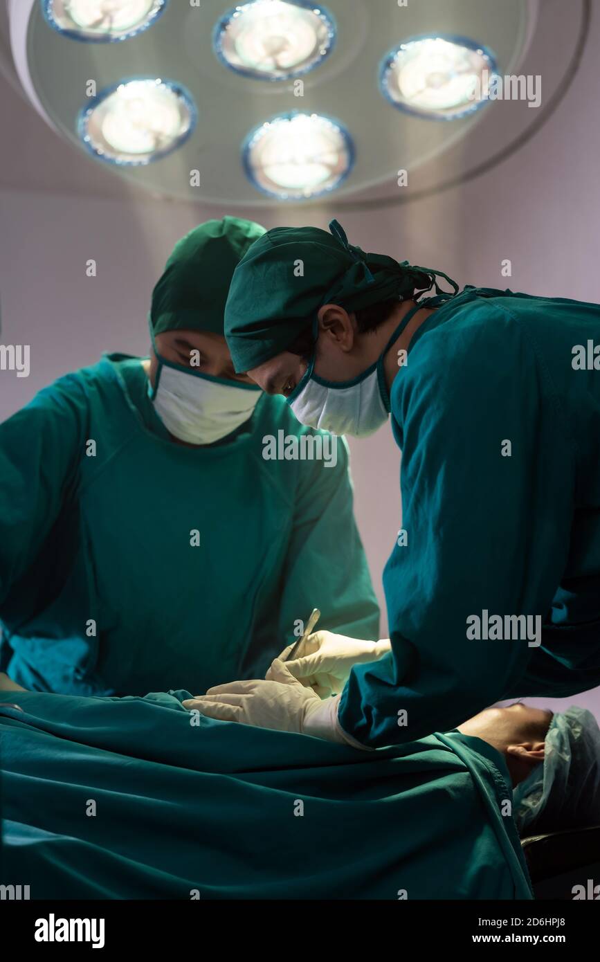 Surgeon doctor and nurse performing Surgical Operation to patient with ...