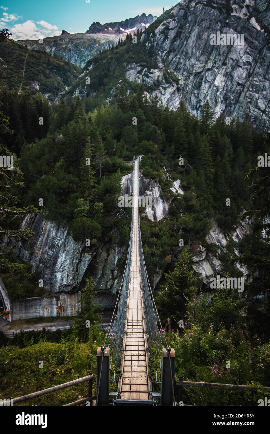 Wooden long footbridge above the deep gorge with a river beach at the ...