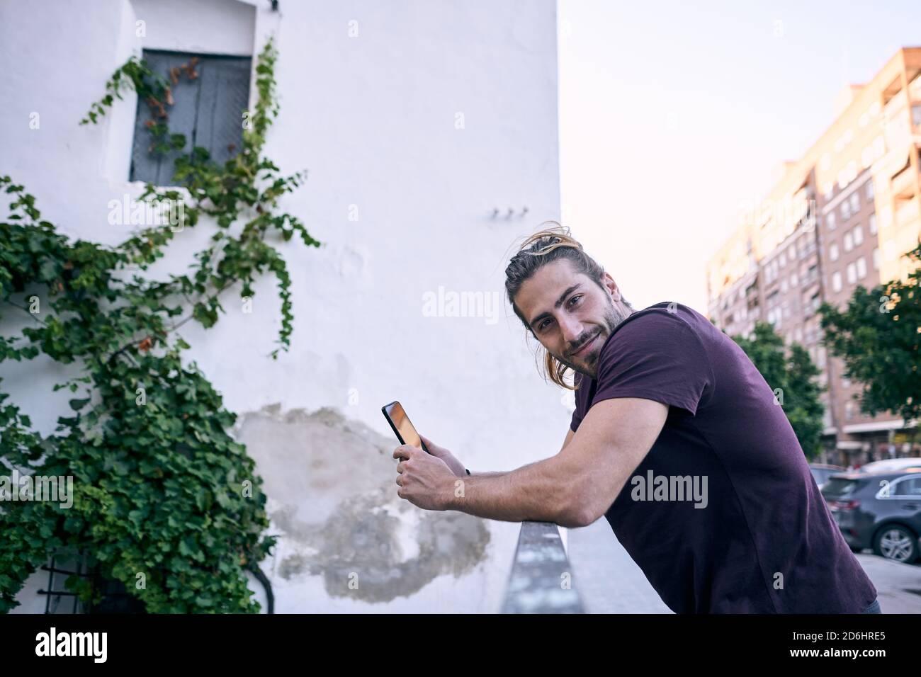 Eye-level shot of a cheerful handsome man holding his smartphone while ...