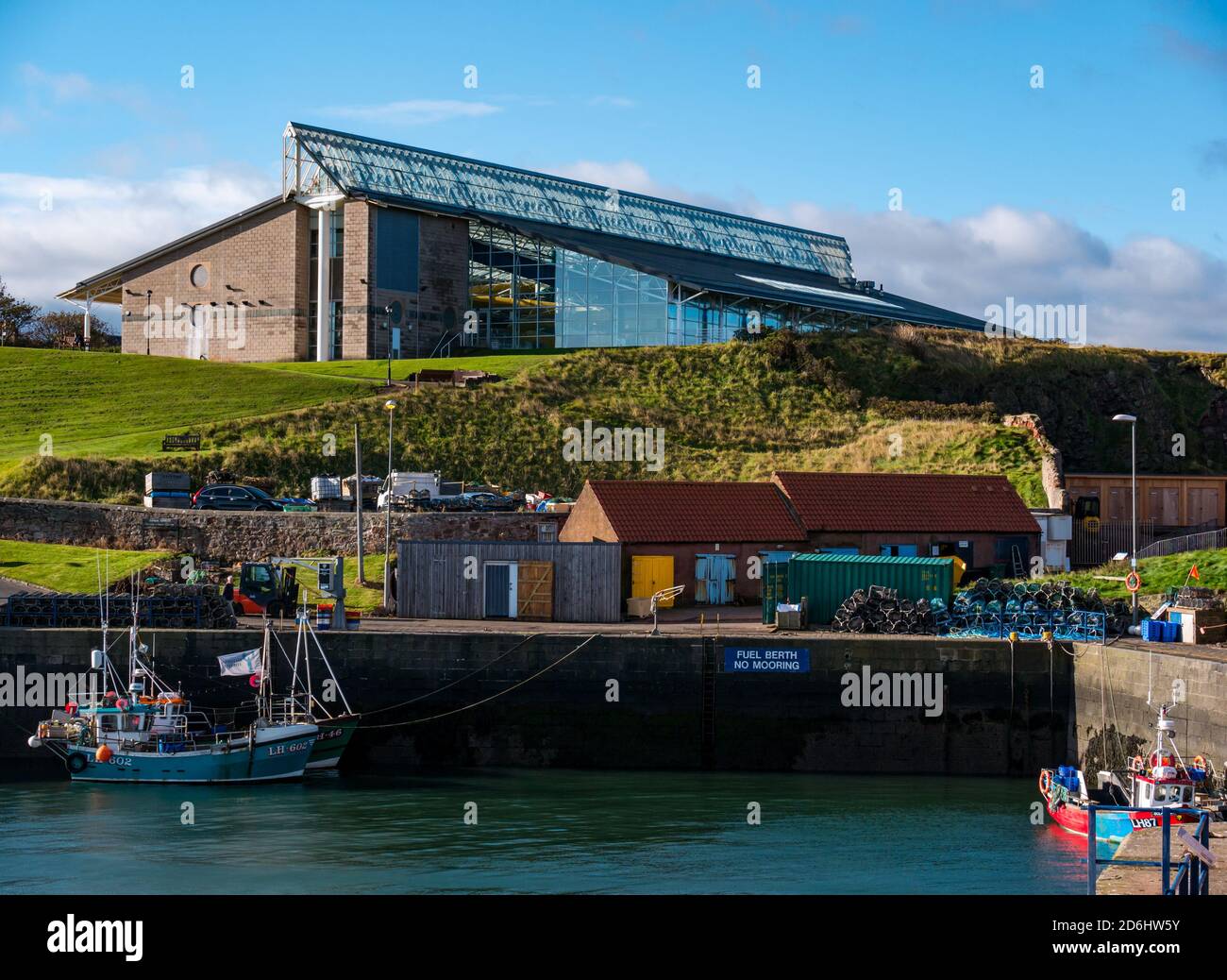 Dunbar Leisure Centre viewed across the harbour with a fishing boat ...
