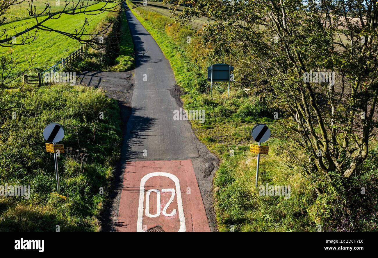 Country road with 20 mph speed limit painted on tarmac on sunny day ...