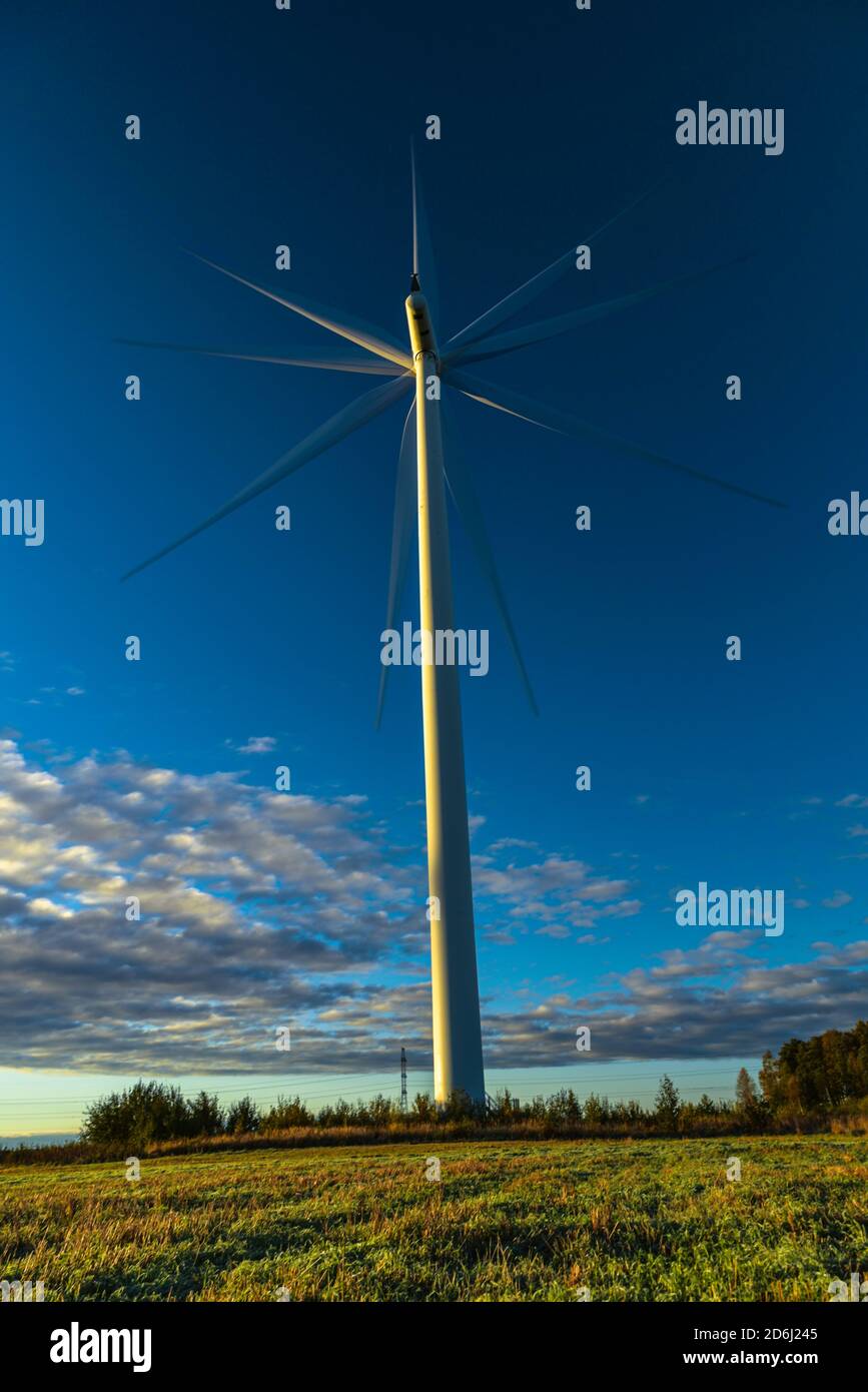 wind generator in white rotates on a background of blue sky with clouds ...